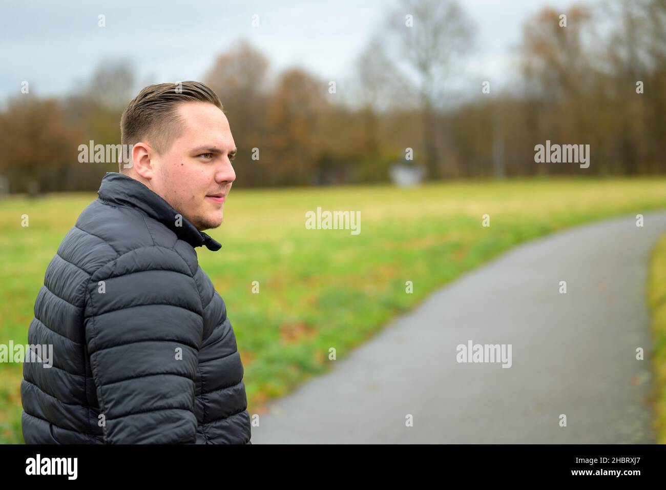 Young man turning back to look over his shoulder as he walks along a ...