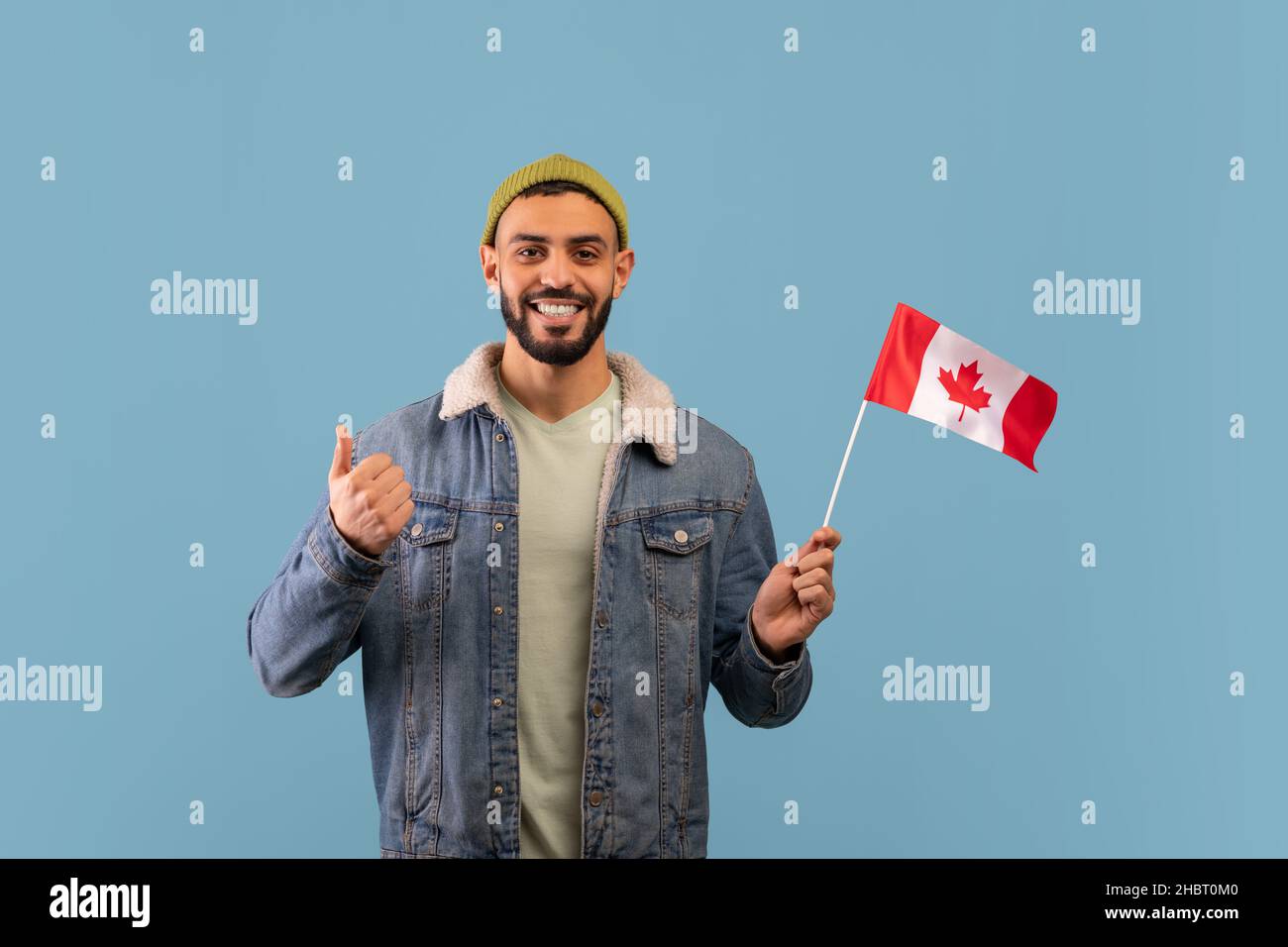 Excited middle eastern man showing thumb up and Canada flag, standing ...