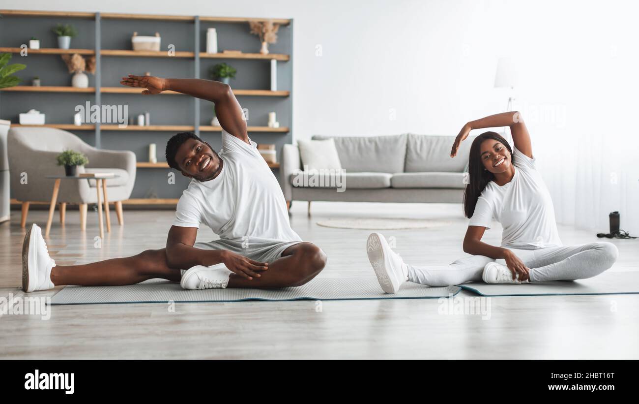Young black couple doing side bend stretch exercise together Stock ...