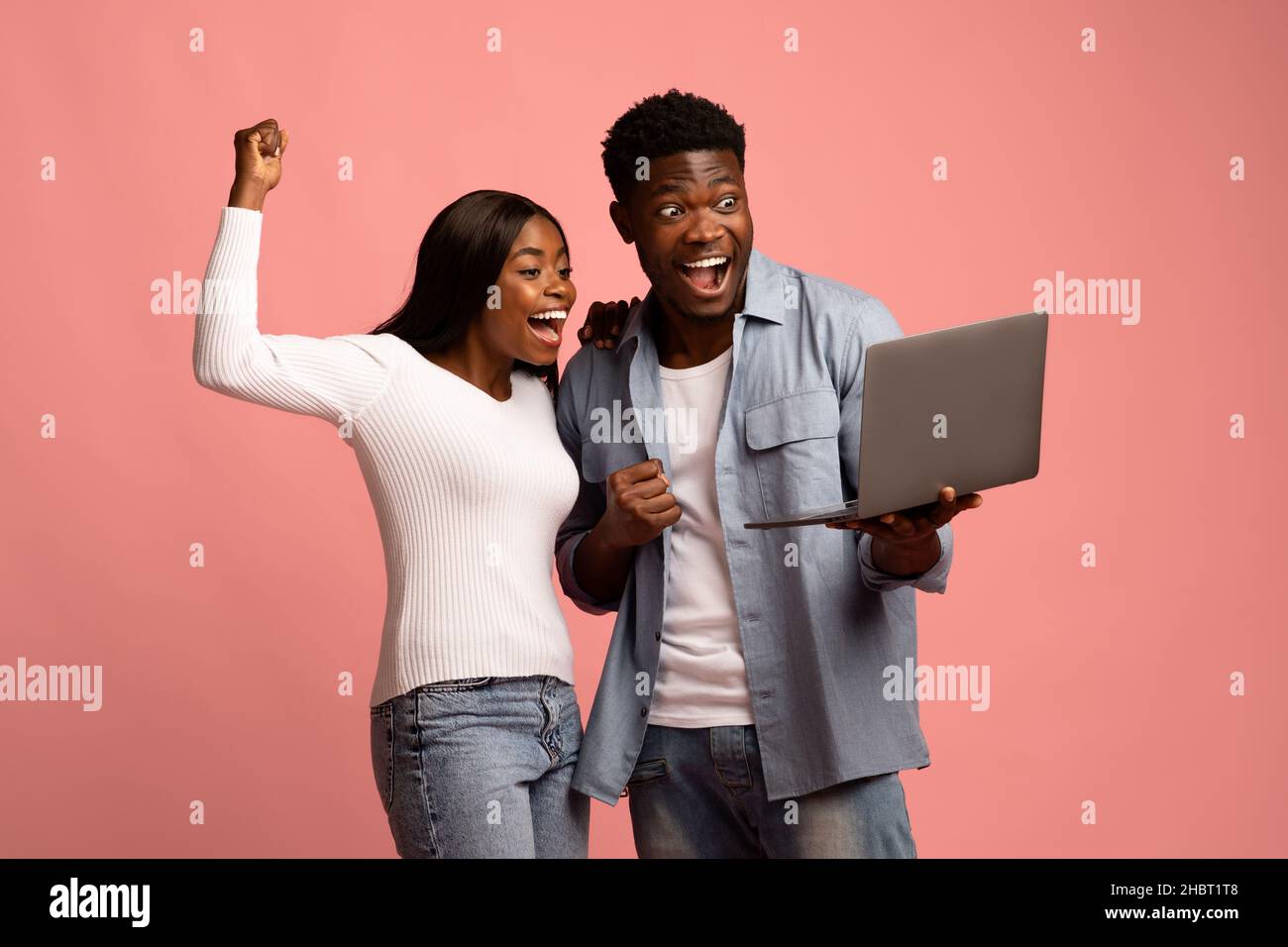 Excited black couple celebrating win with laptop Stock Photo - Alamy