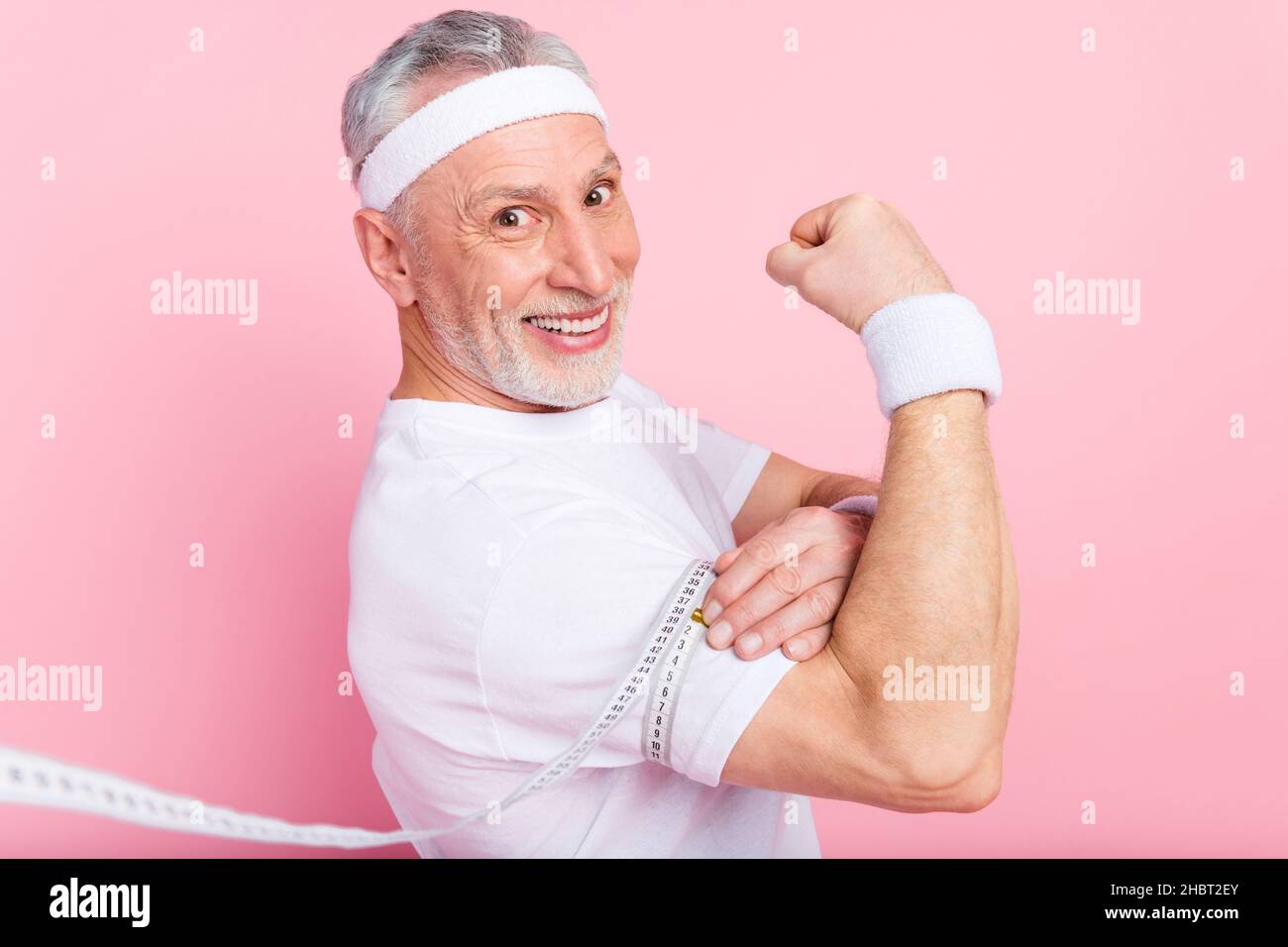 Photo portrait of senior man smiling measuring biceps muscles with tape ...