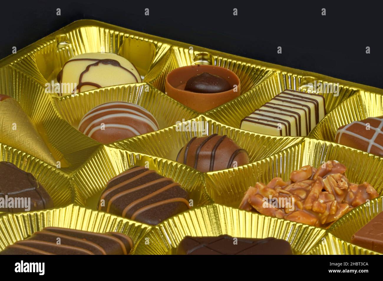 Different chocolate pralines in a golden box. Close up shot of ...