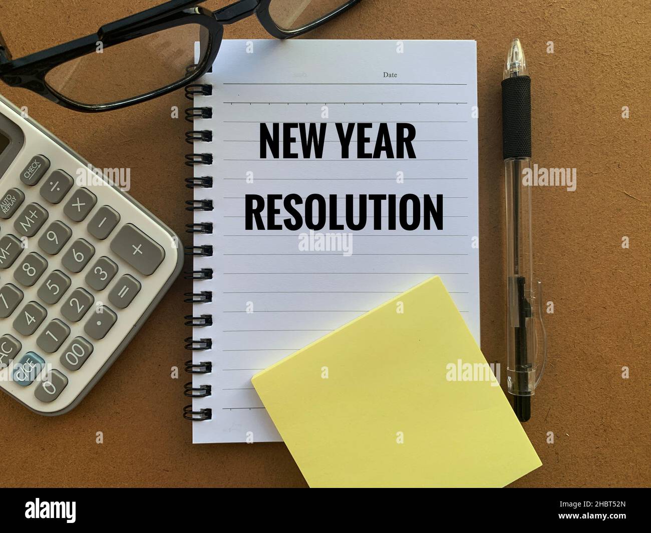 New year resolution text on note pad with pen, glass, calculator and ...