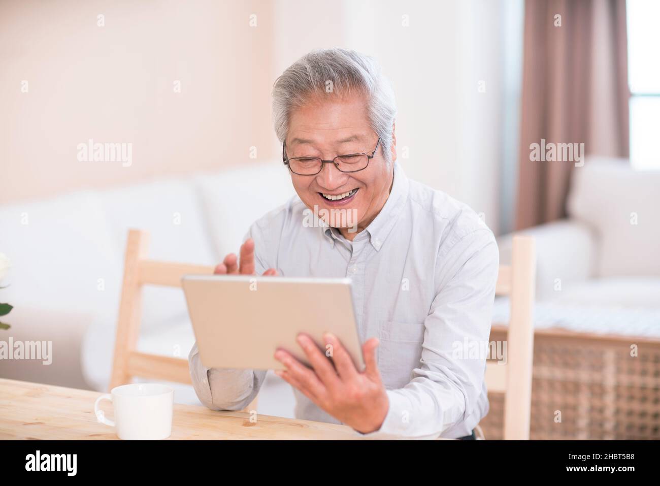 Old man using a tablet computer to make a video call at home Stock ...