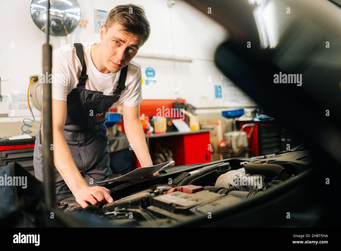 Portrait of confident handsome professional male car mechanic in blue ...