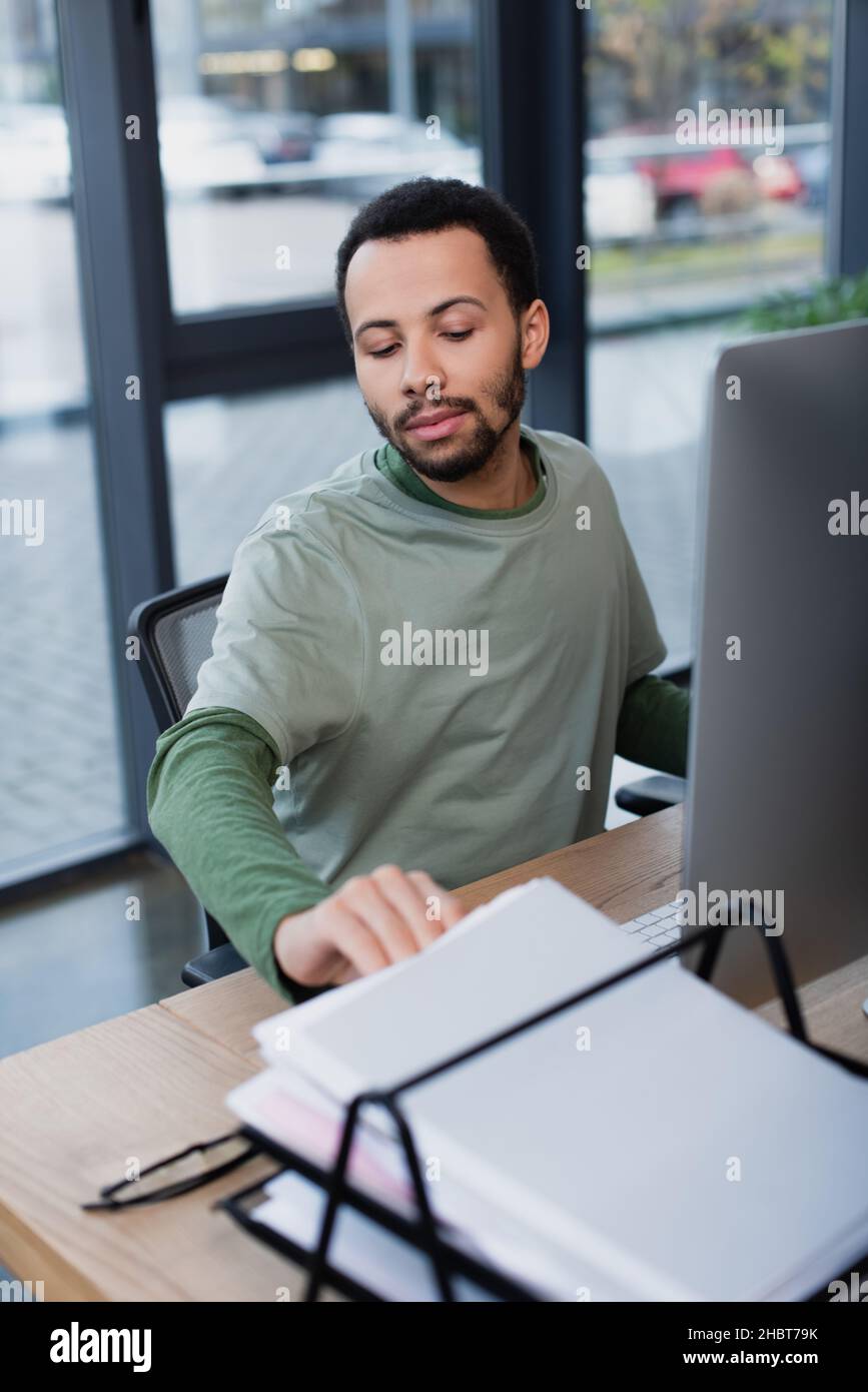 bearded african american man looking at documents on document tray near ...