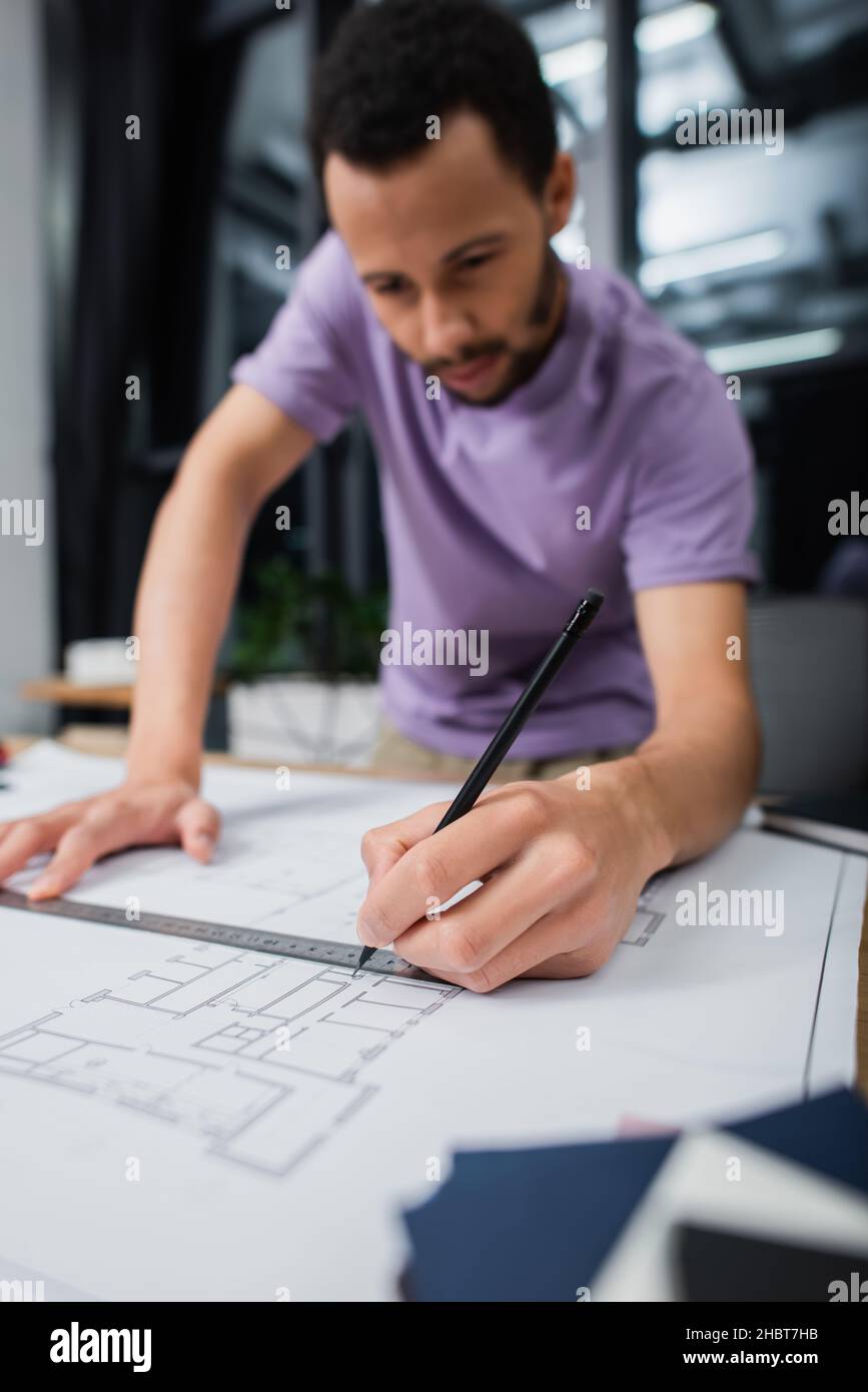 african american architect holding pencil and ruler near blueprint ...