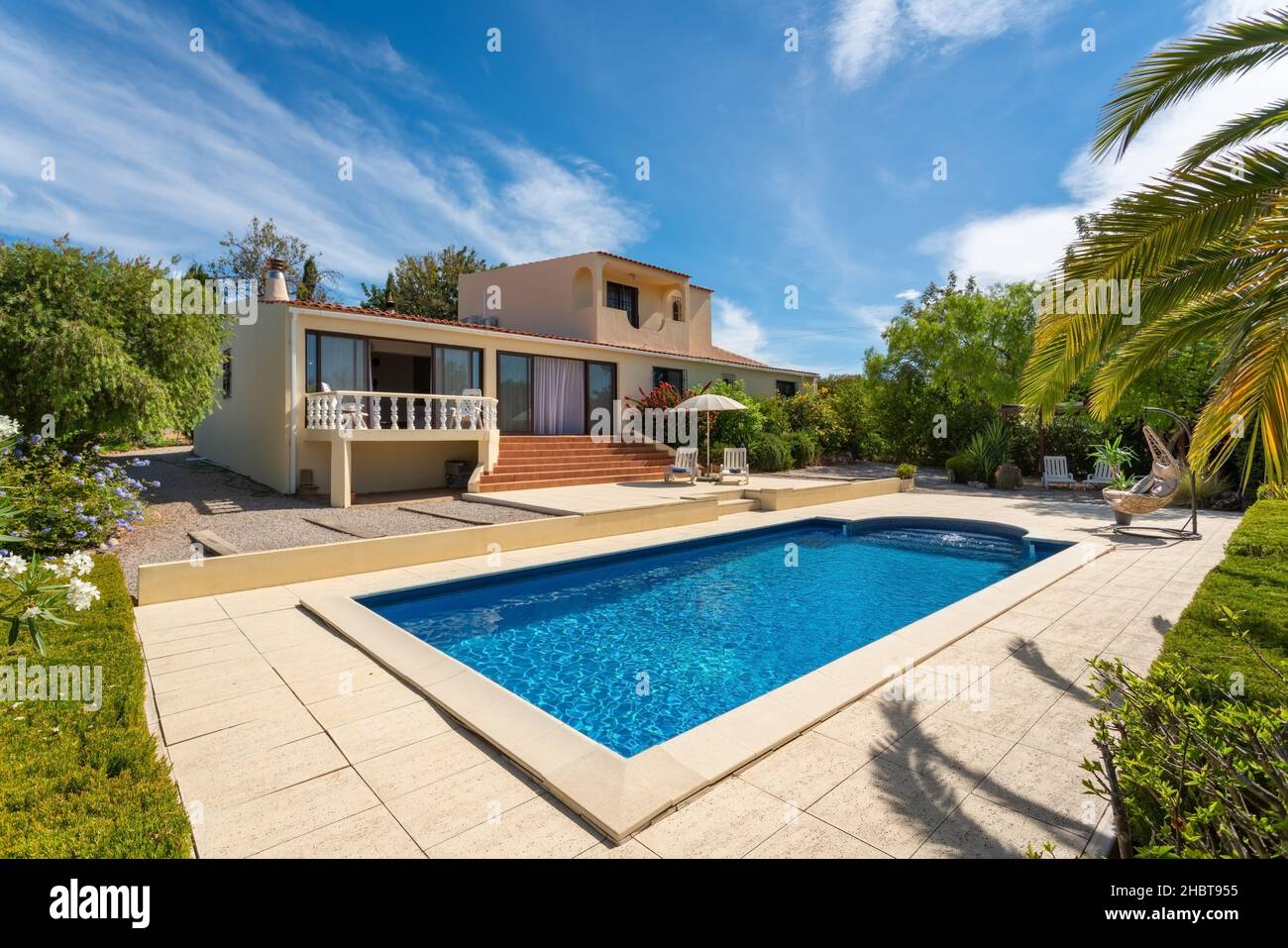 Modern villa with pool and tropical garden with palm trees and rocking ...