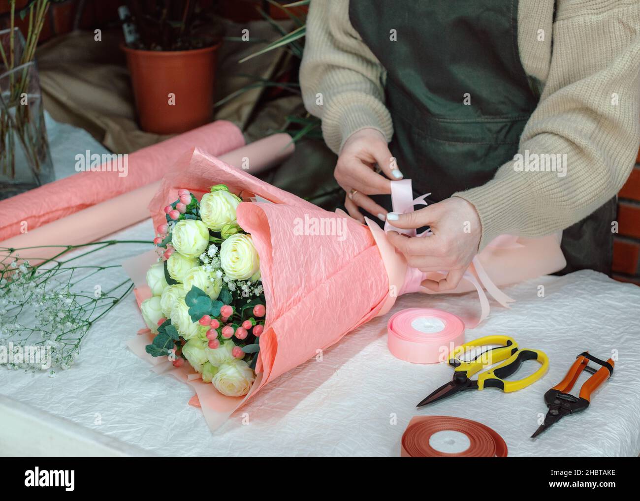 Female florist creating beautiful bouquet at workplace in flower shop ...