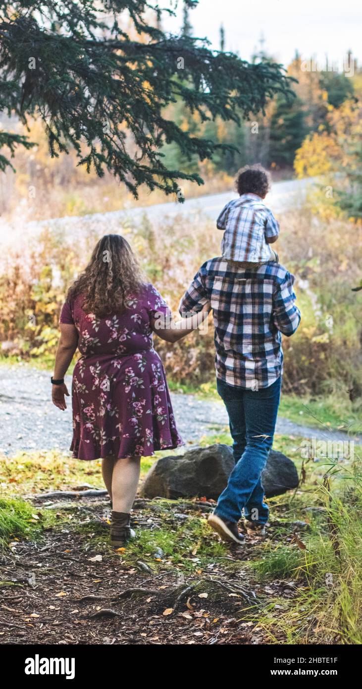 A vertical shot of the back view of the beautiful family in the forest ...