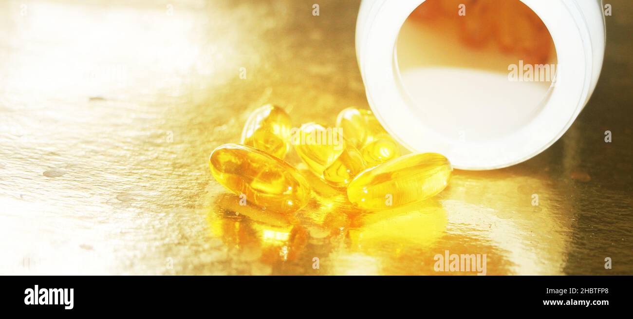 Soft gels pills with Omega-3 oil spilling out of pill bottle close-up ...