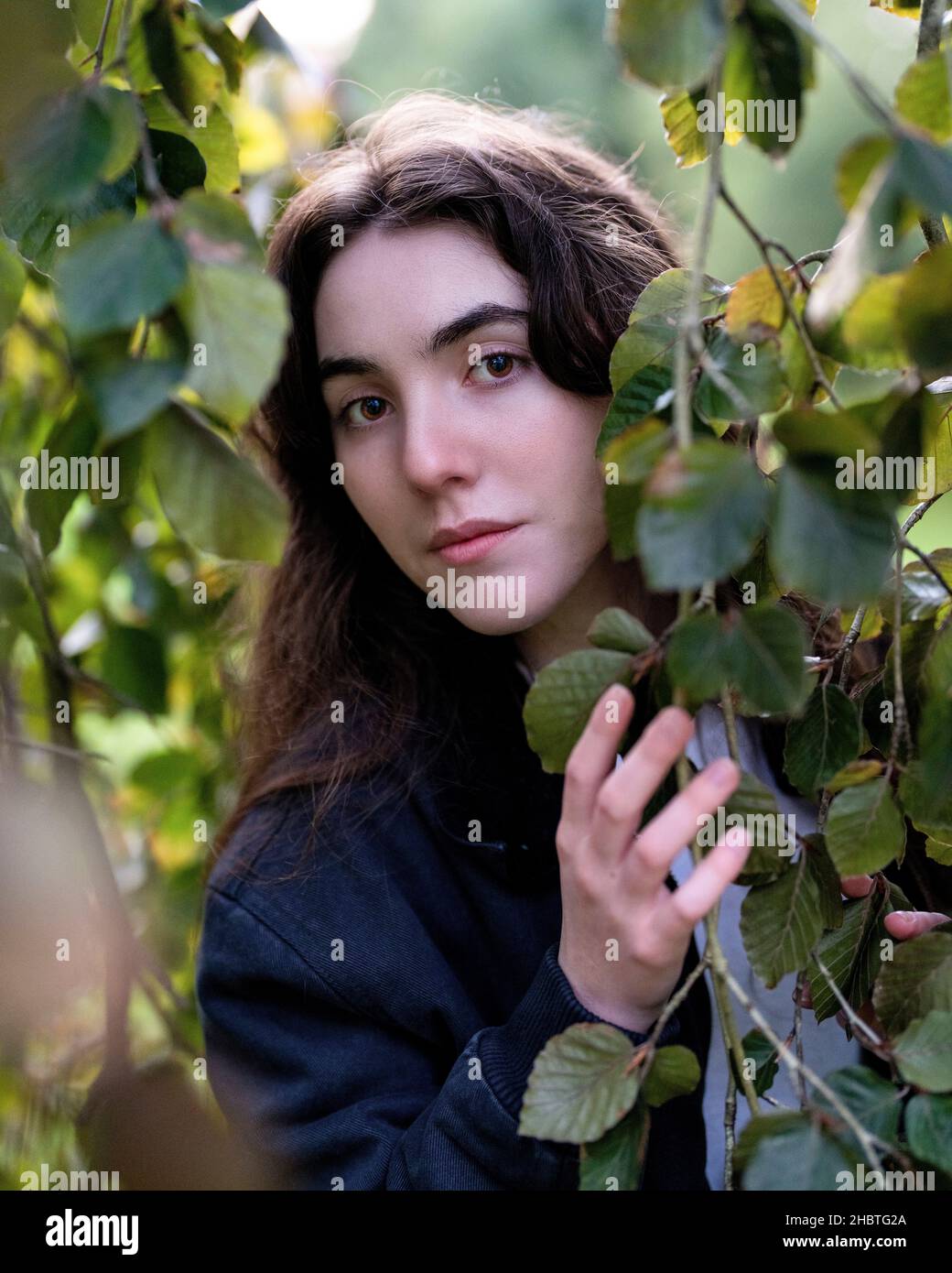 Teenage Woman Standing Surrounded by Trees Stock Photo - Alamy