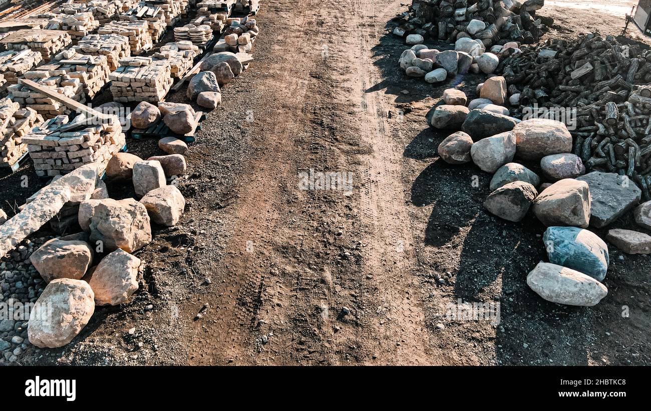 Landscaping rocks on pallets off to the side of the narrow dirt road ...