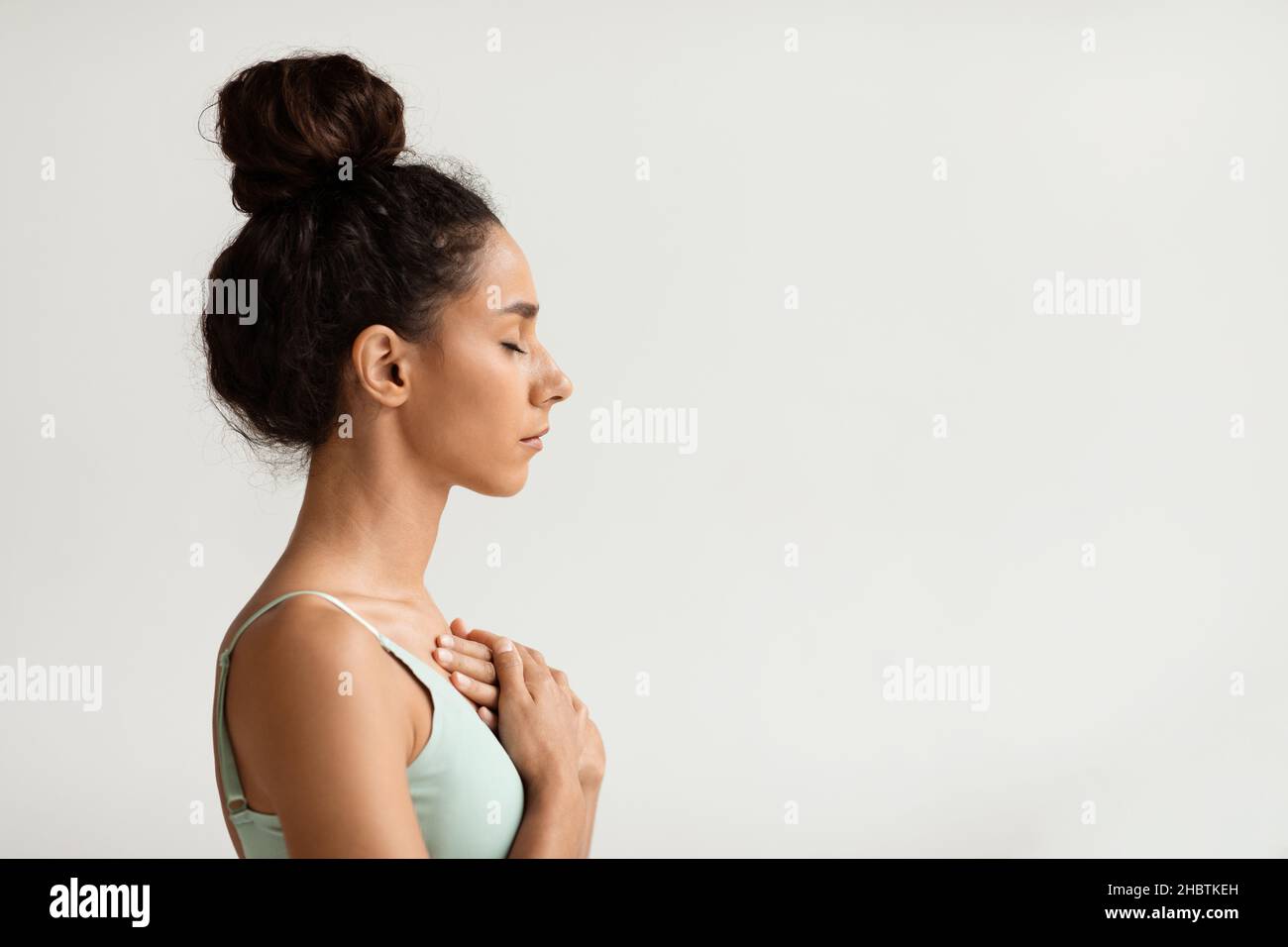 Profile of calm young woman with hands on chest and closed eyes Stock ...
