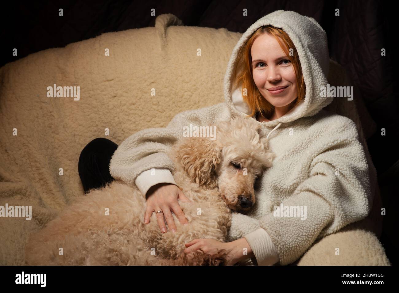 woman lies with a large dog on the couch. The shaggy domestic dog laid ...