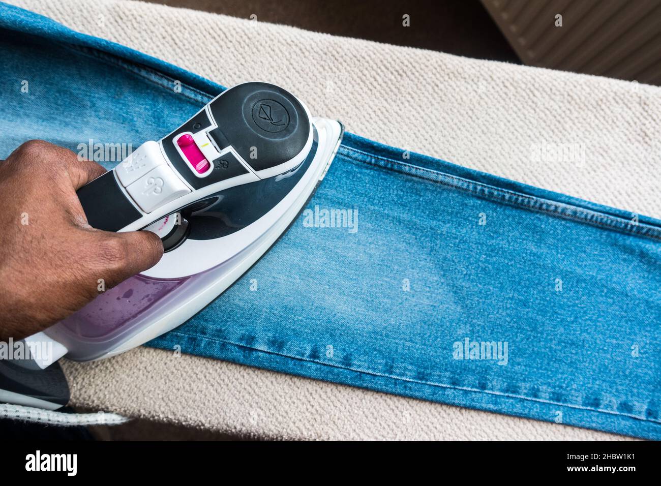 Adult middle aged Indian male pressing Jeans trousers on a Iron board ...
