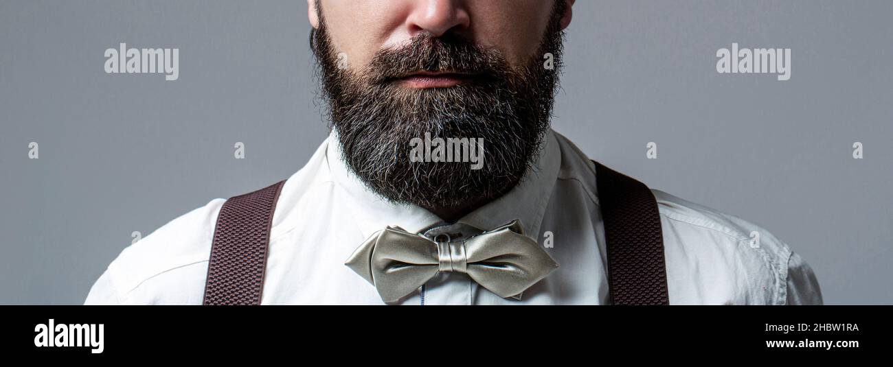Portrait of handsome bearded man in white shirt and bow tie, suspenders ...