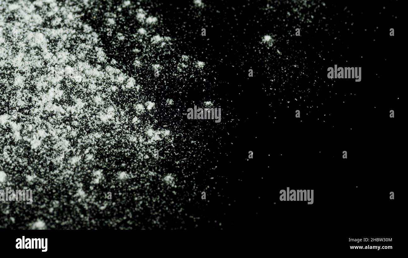 White powder falling down isolated on black background. White dry inks ...