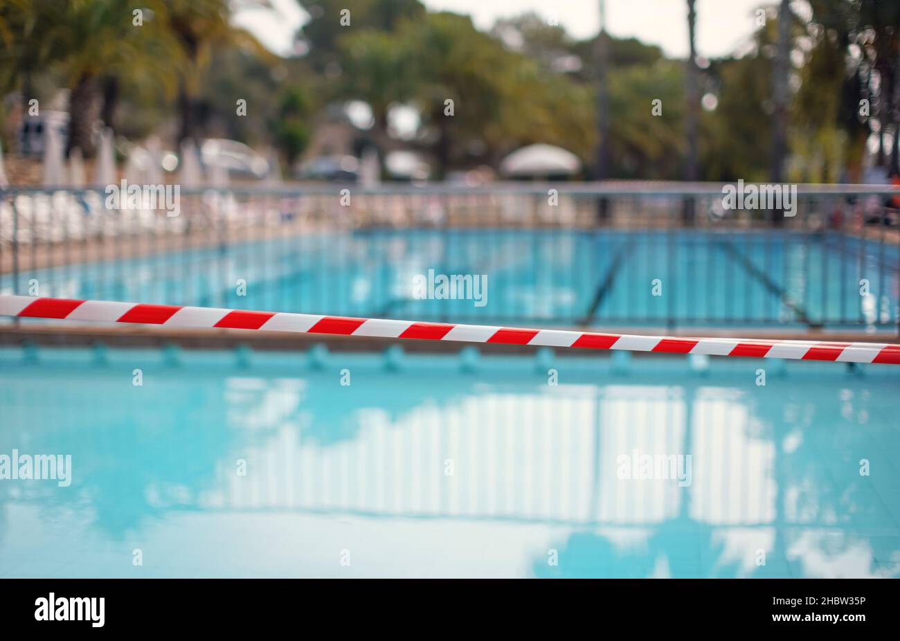 Red white tape in front of empty hotel resort swimming pool closed ...