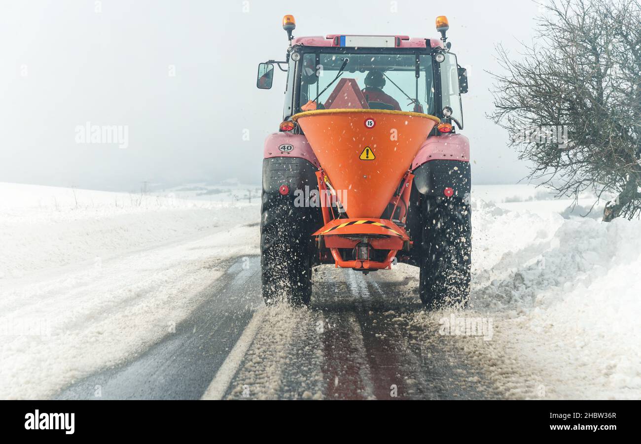 Small gritter maintenance tractor spreading de icing salt on asphalt ...