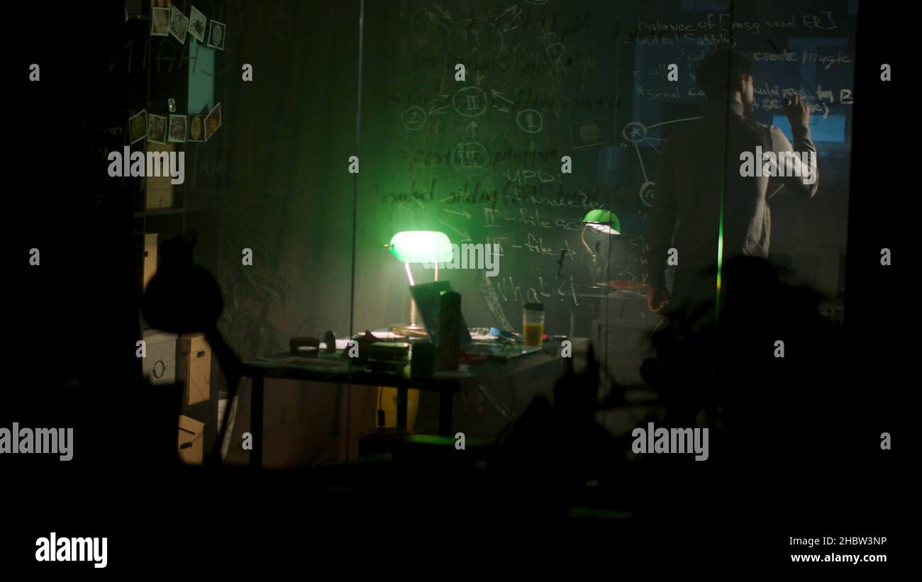 Businessman writing notes on the glass board near the mess on his table ...