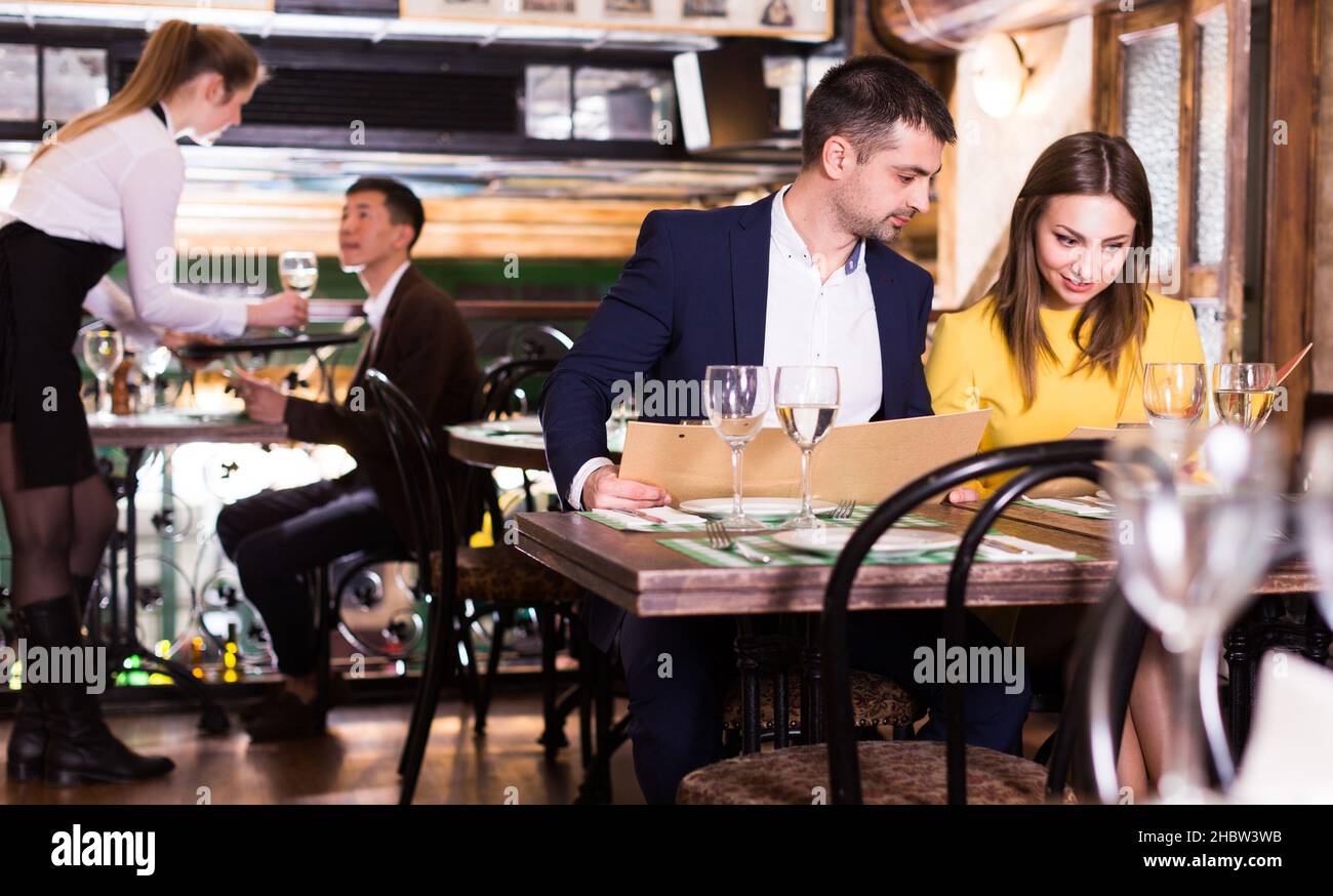 Couple with menu is choosing order in time dinner Stock Photo - Alamy