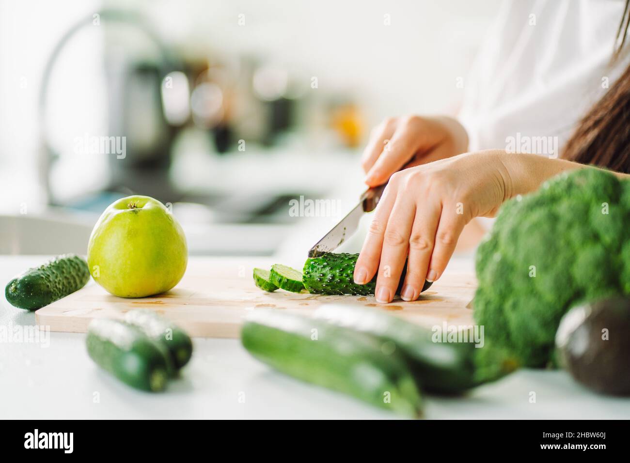 Woman preparing food in her kitchen. Female chopping fresh green ...