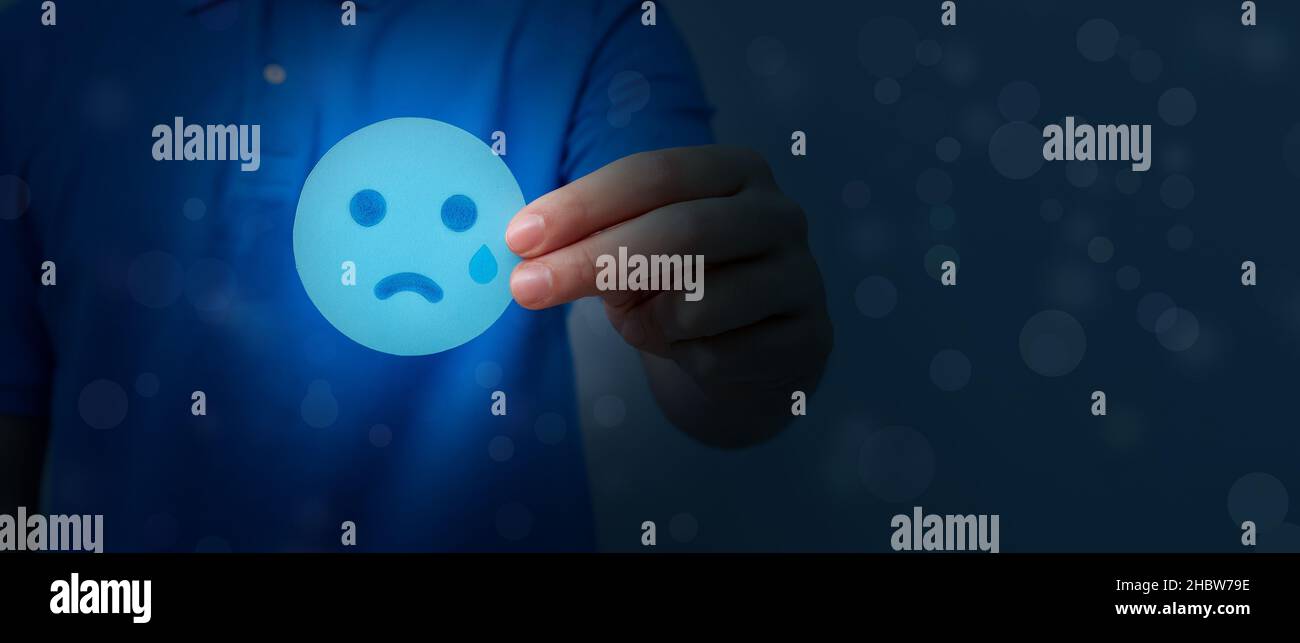 A hand holding a blue sad face sign - the blue Monday concept Stock ...