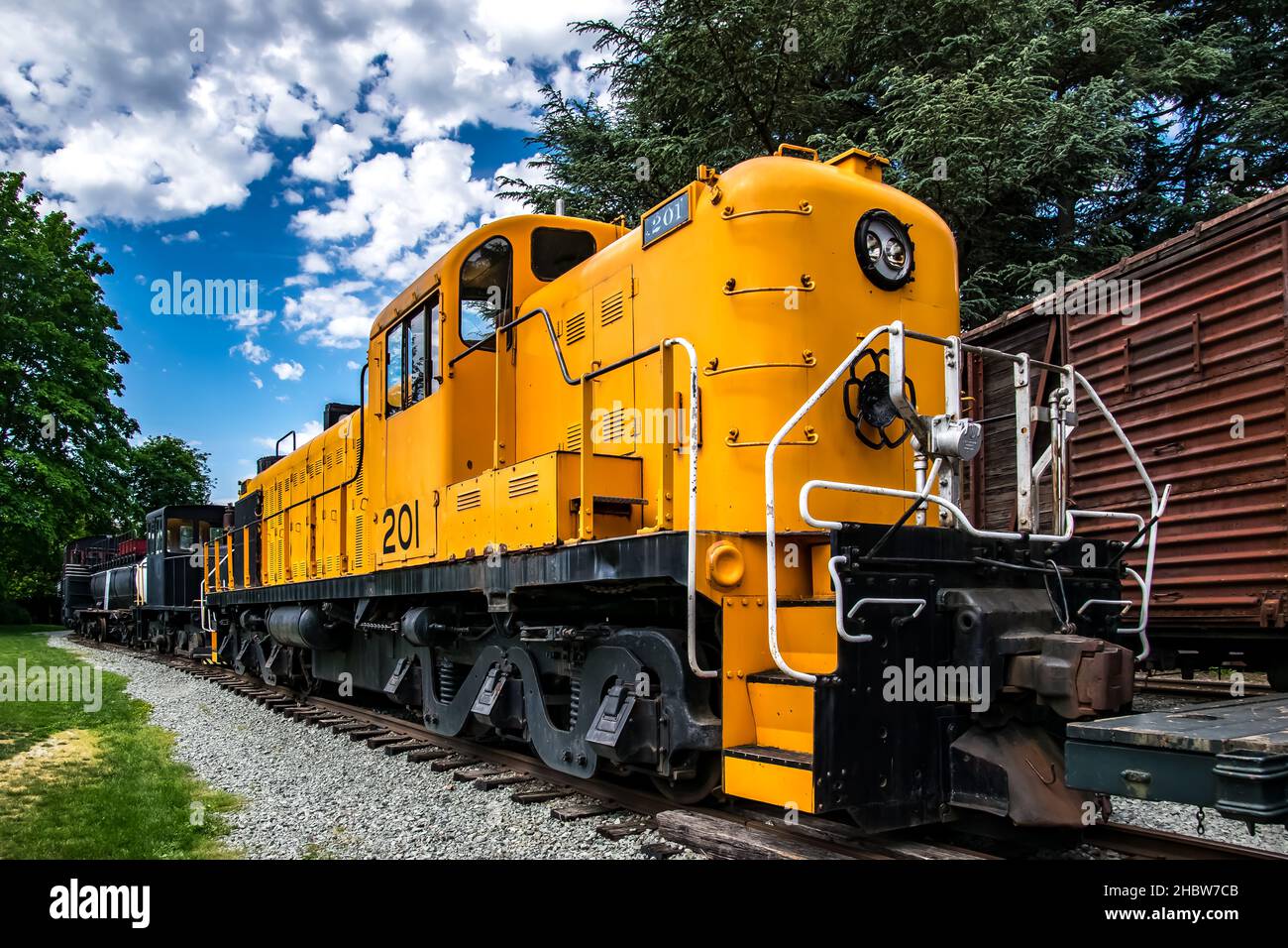 The yellow locomotive on the rails against a cloudy sky amid fields ...