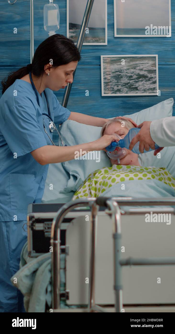 Doctor and nurse helping elder patient with disease in bed. Medical ...