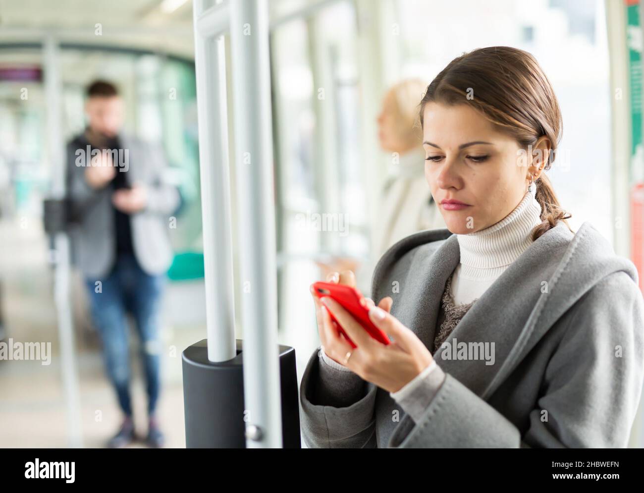 Young woman with phone in public transport Stock Photo - Alamy