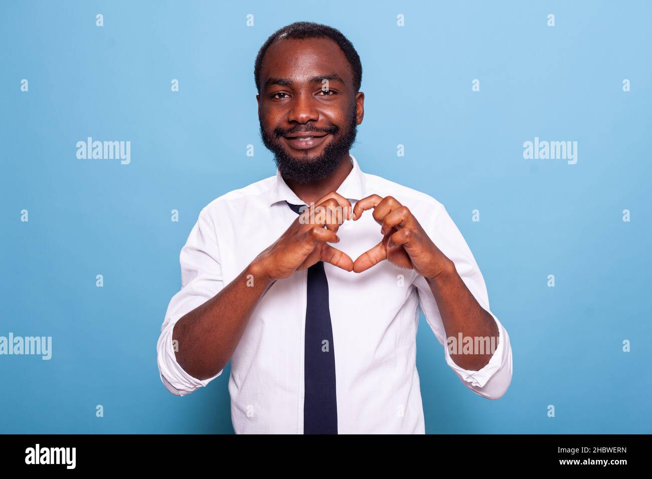 Portrait of smiling influencer making heart shape with hands to show ...