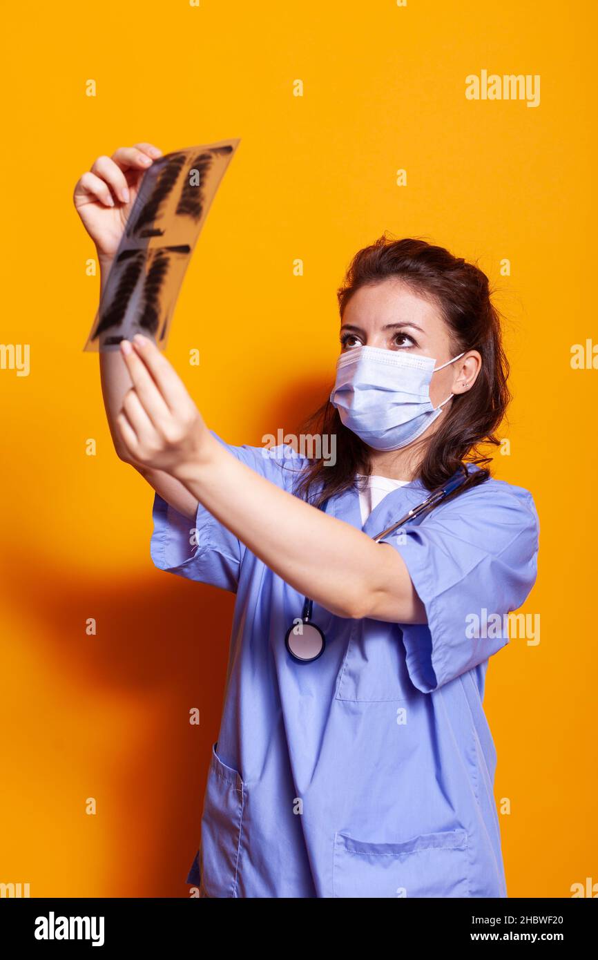 Medical assistant wearing face mask and looking at x ray to find ...