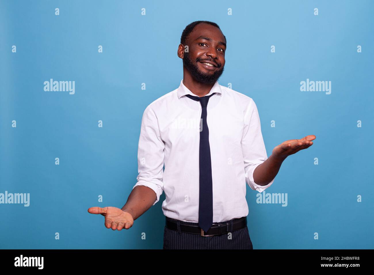 Portrait of smiling businessman with open palms weighing options on ...