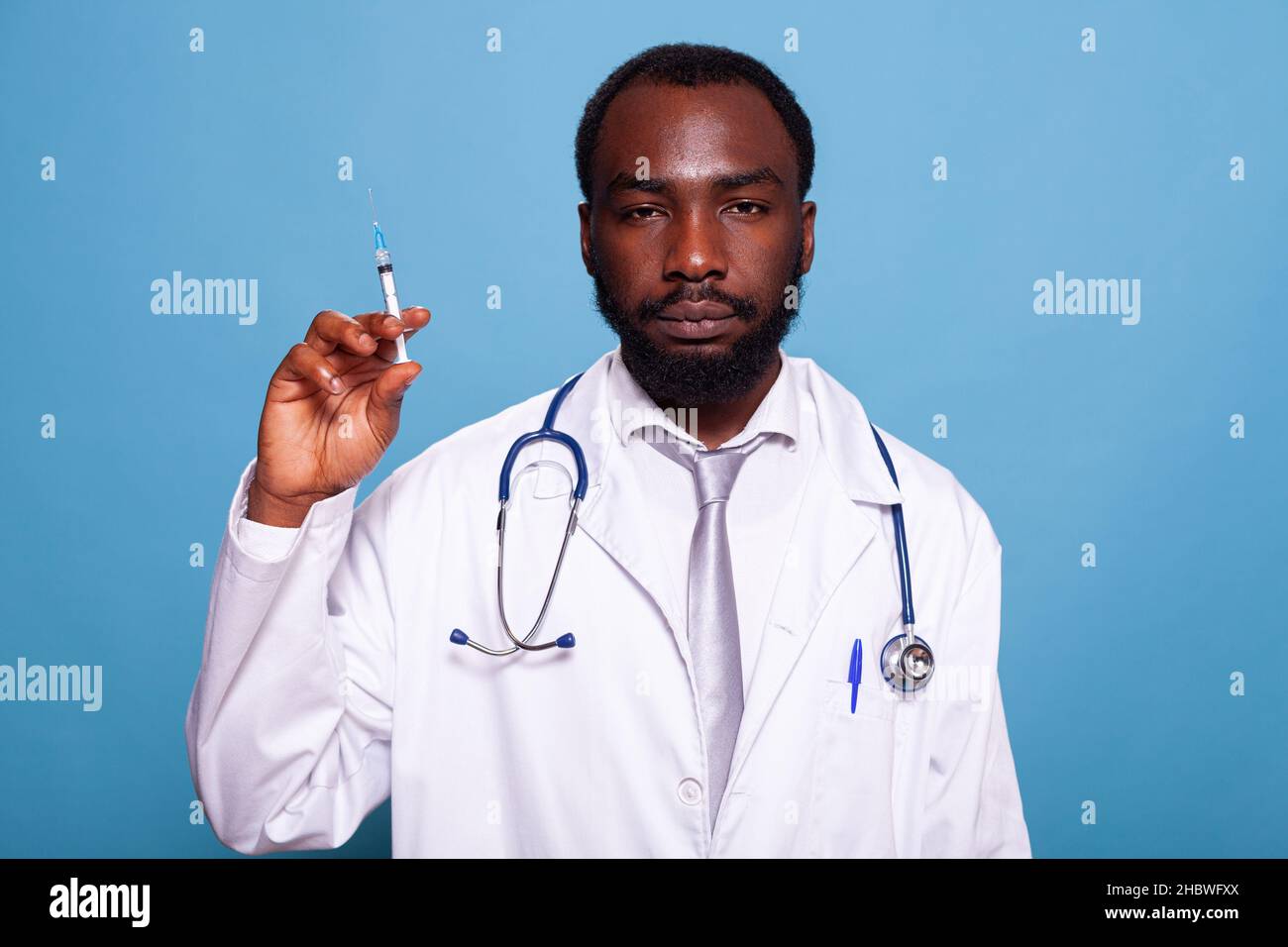 Confident doctor in white lab coat holding syringe with hypodermic ...