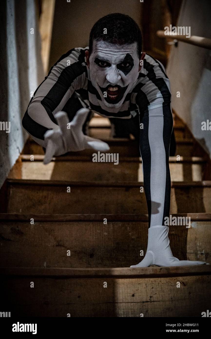 A vertical shot of a male in a mime costume posing with a scary ...
