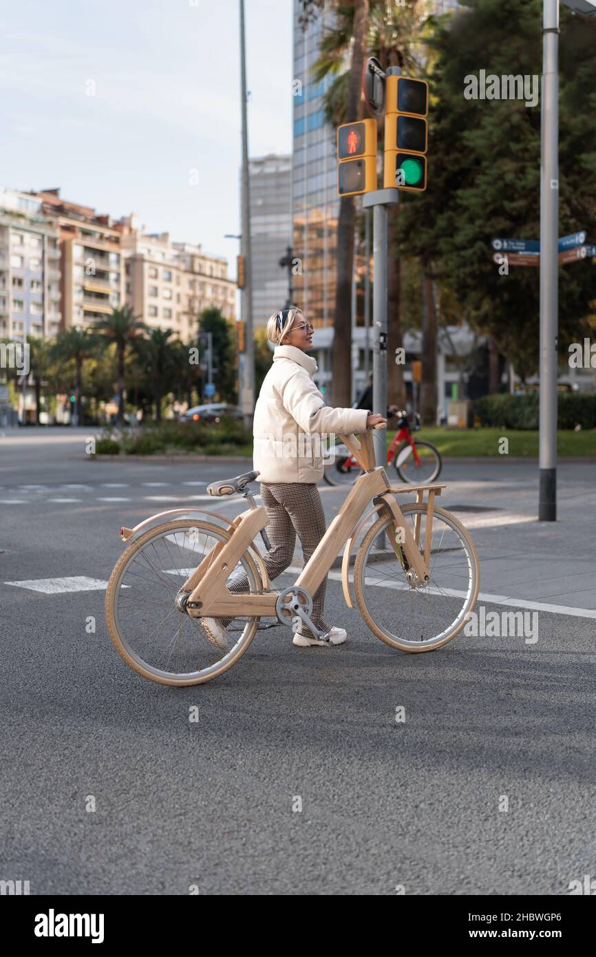 Full body woman with lumber eco bicycle crossing road near traffic ...
