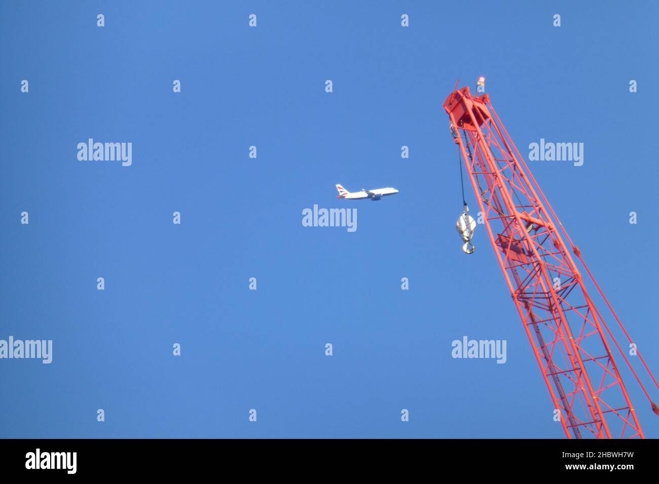A red crane with blue sky and a plane on the background Stock Photo - Alamy