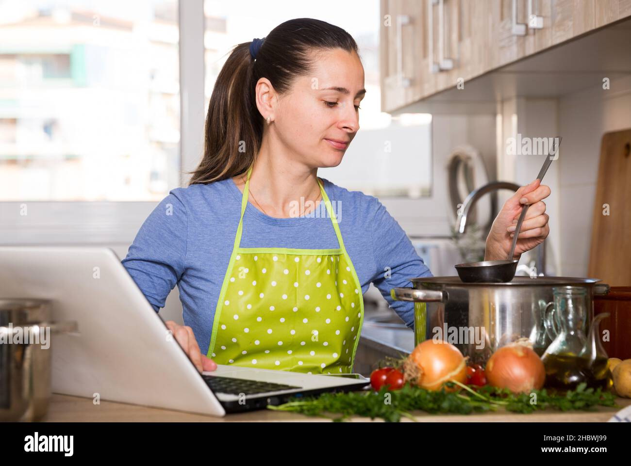 Young woman cooking recipe from the Internet Stock Photo - Alamy