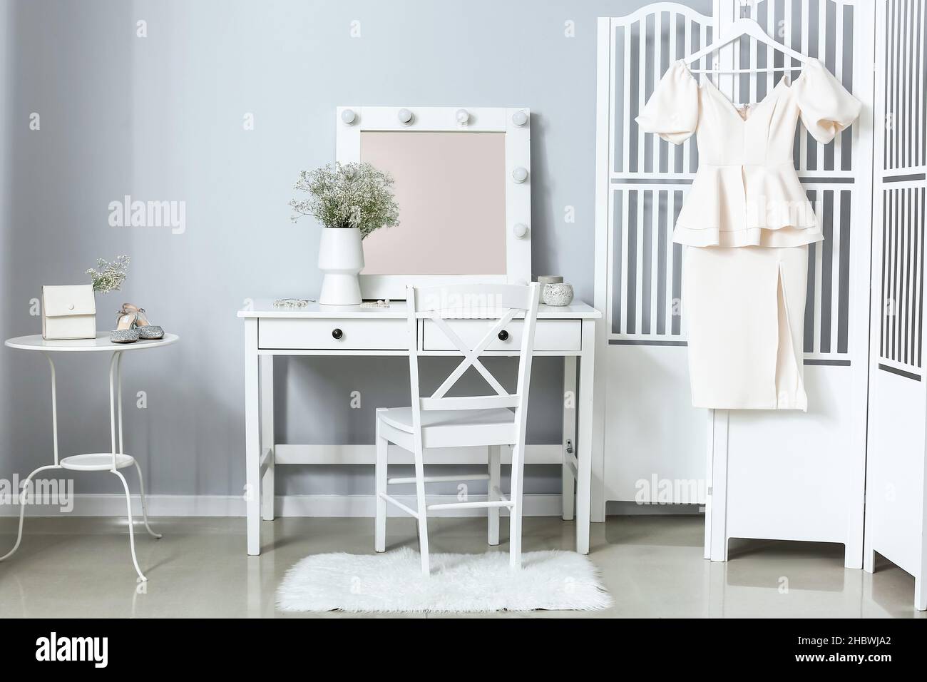 Interior of light dressing room with table, folding screen and ...
