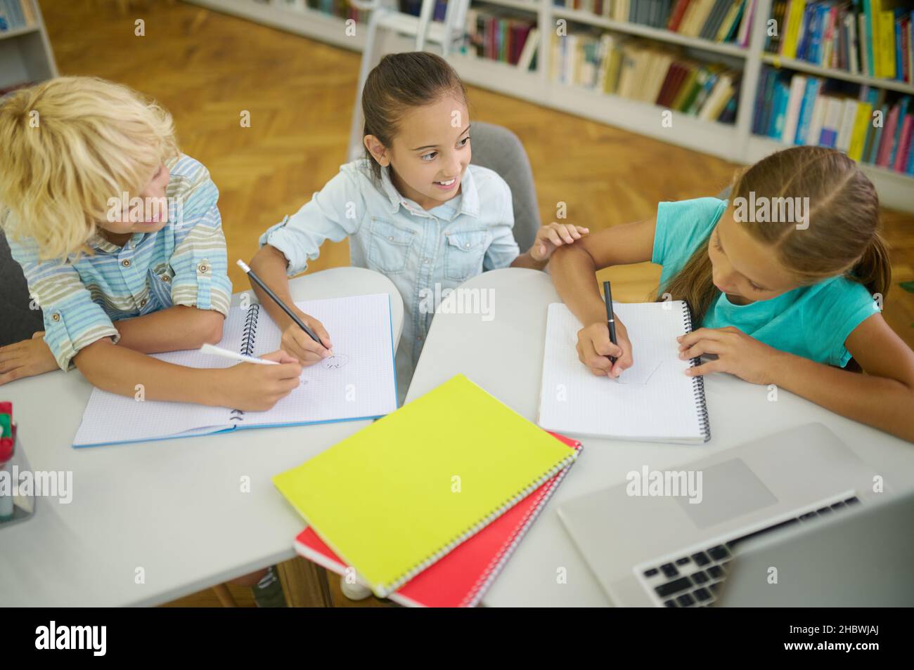 Top view of children writing at table in library Stock Photo - Alamy