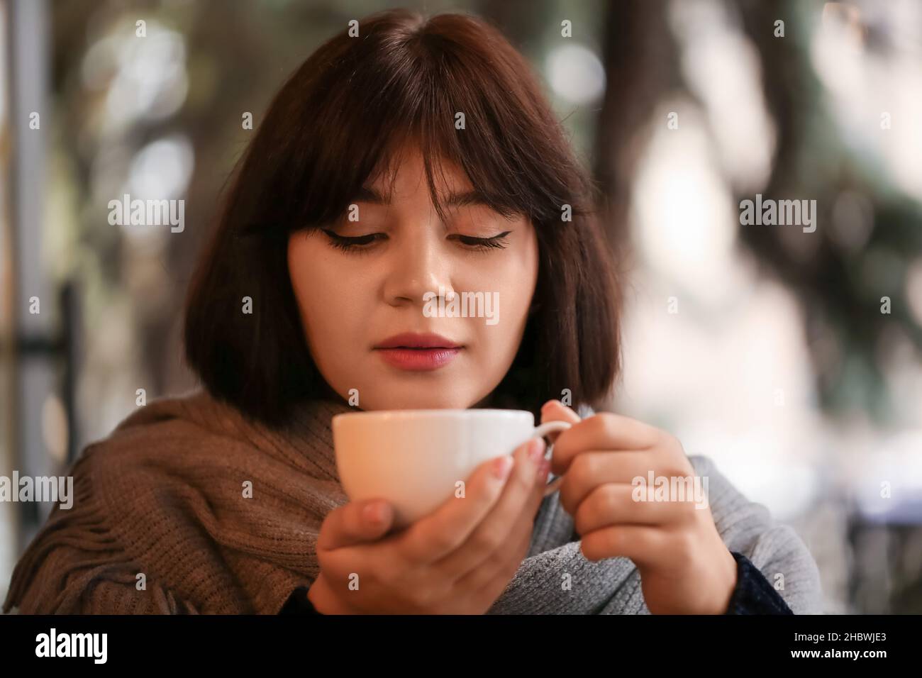 Beautiful young woman drinking tea in outdoor cafe Stock Photo - Alamy