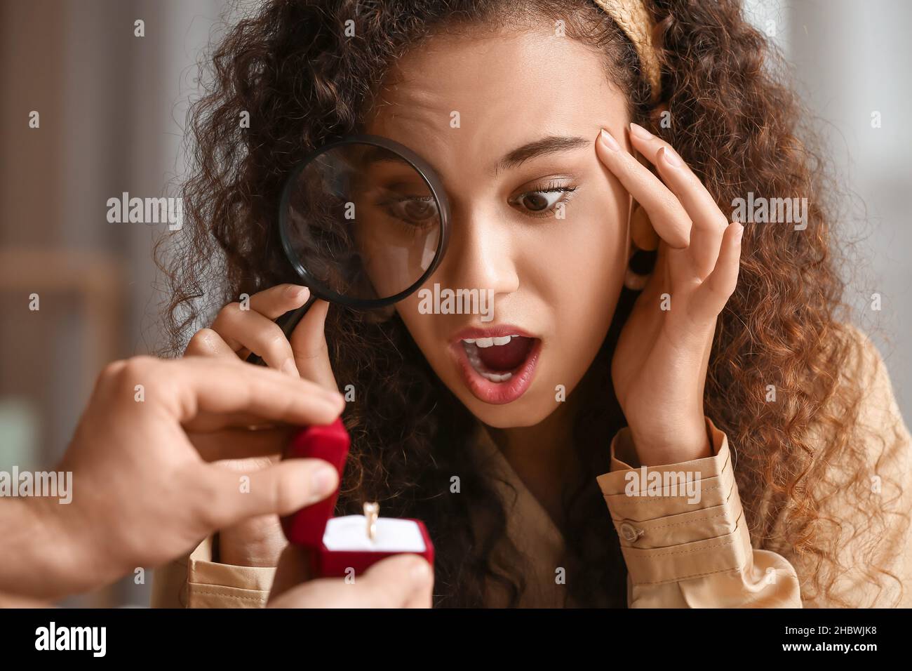 Surprised young African-American woman looking at engagement ring given ...