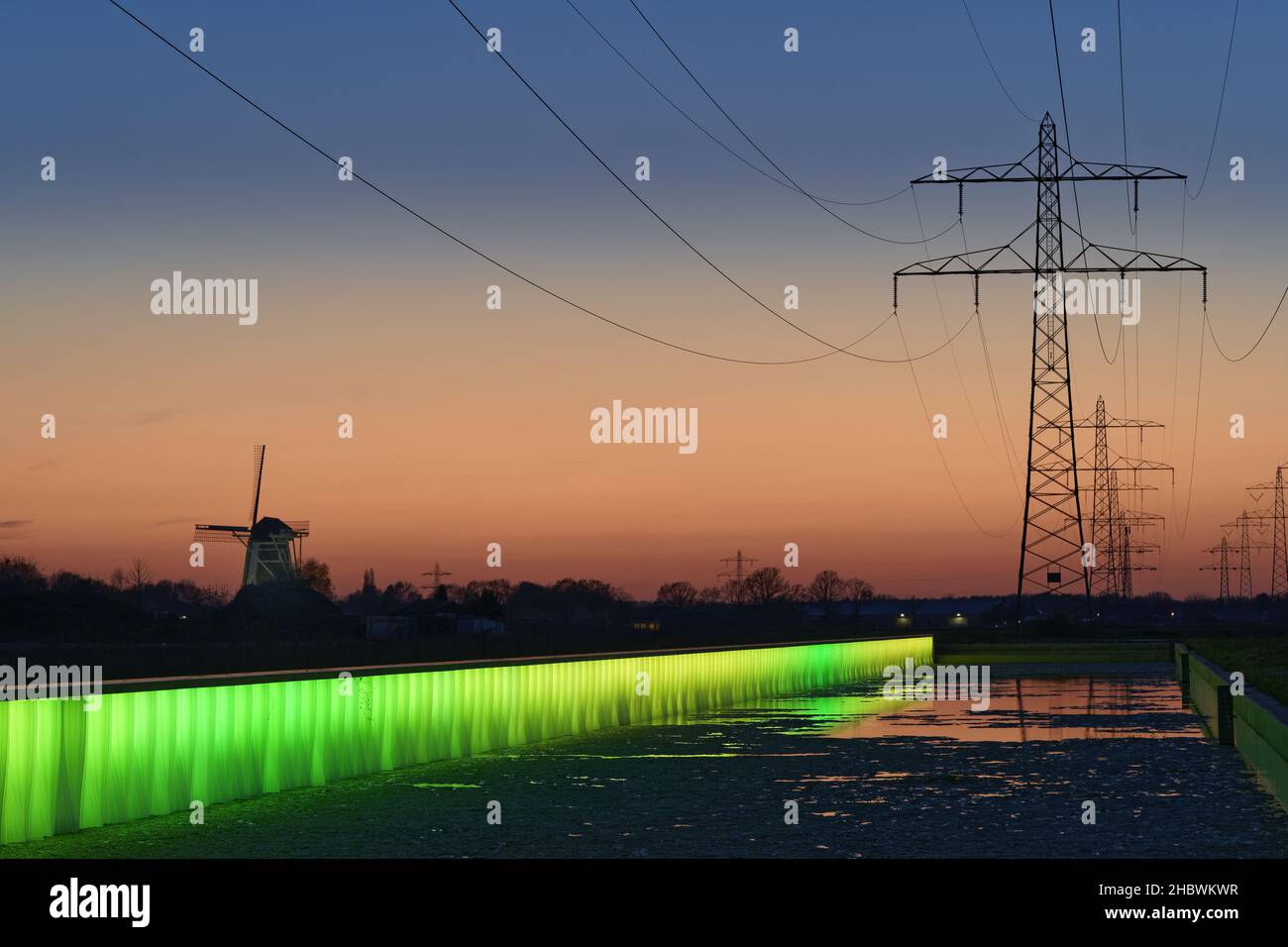 A scenic shot of electricity towers located behind a small water stream ...
