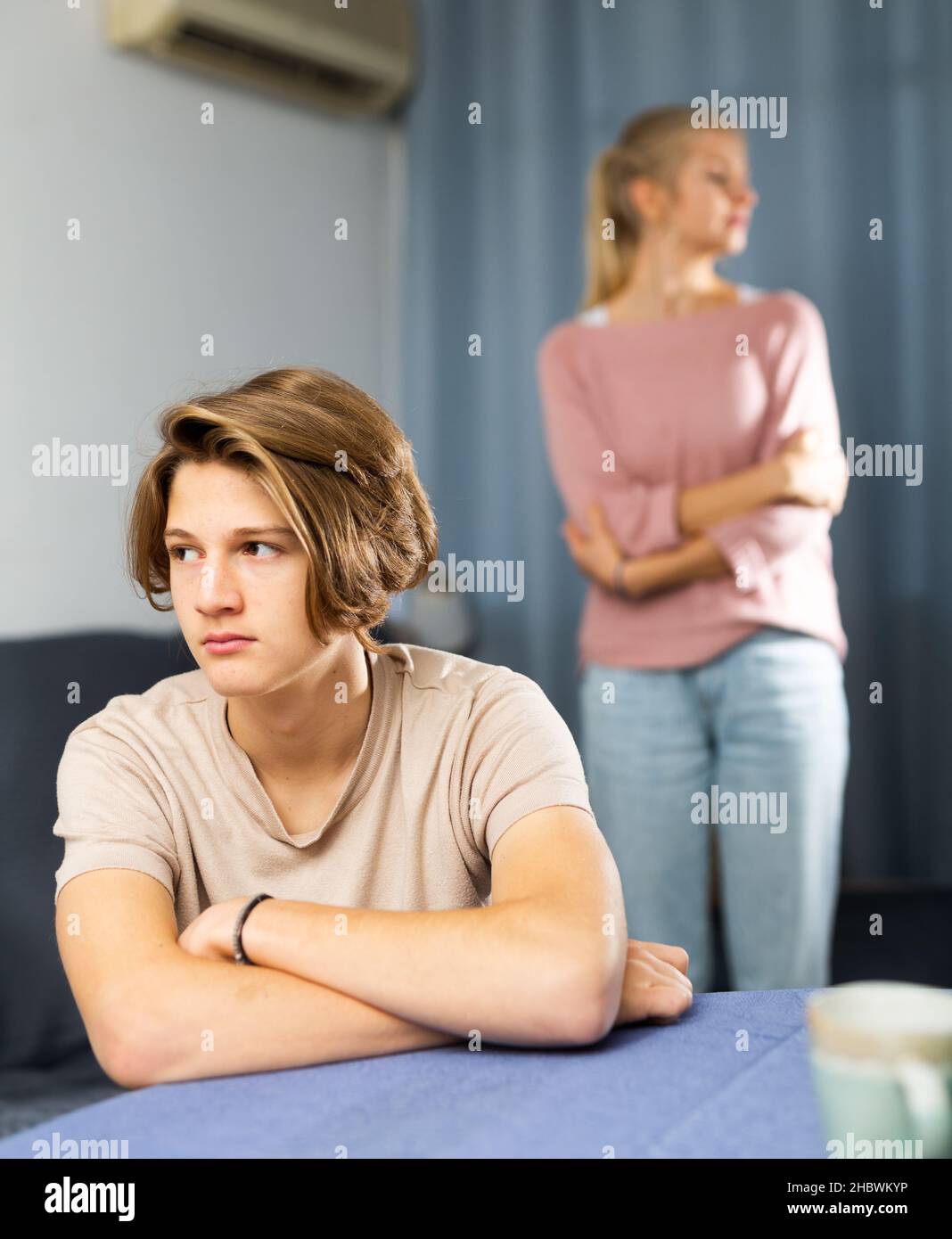 Disappointed teenager sitting at table at home after discord with ...