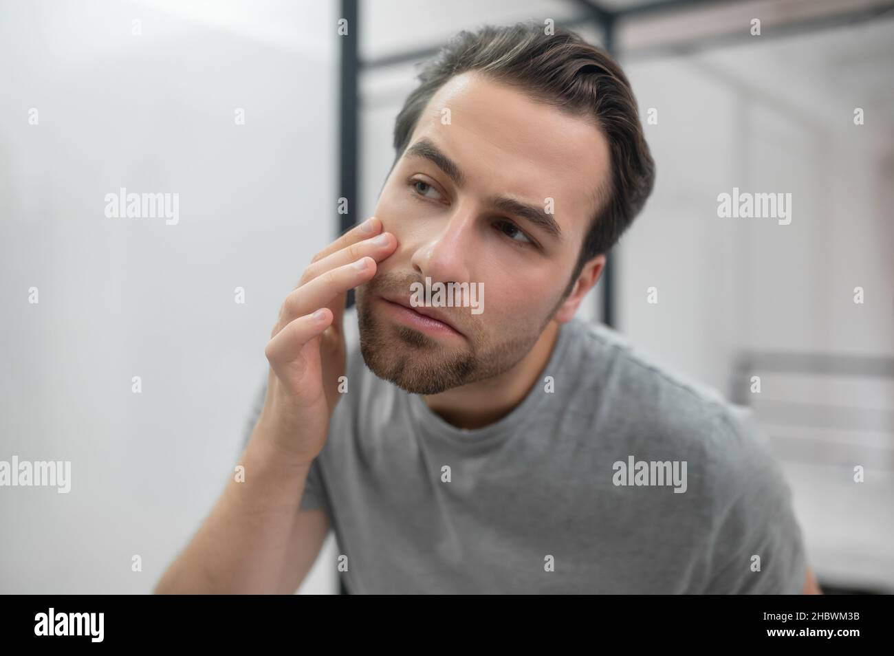 Man near the mirror scrutinizing himself Stock Photo - Alamy