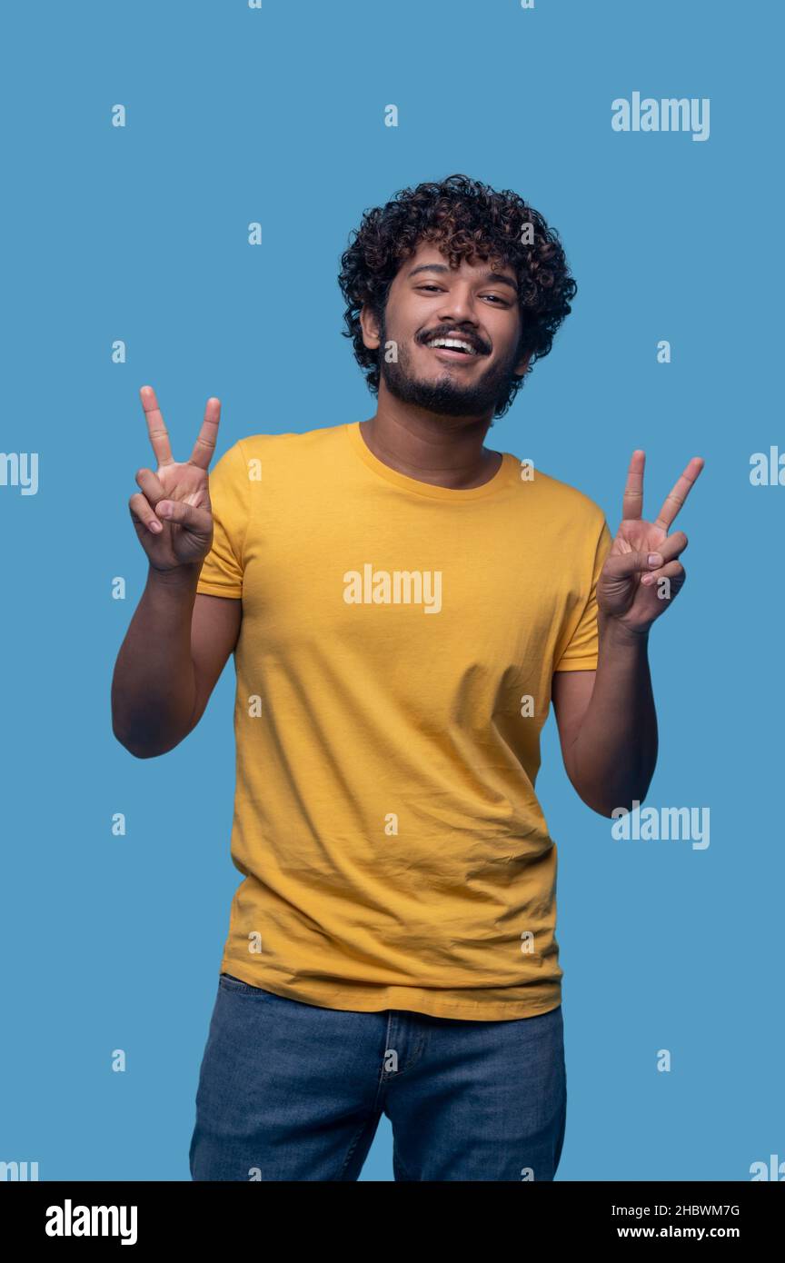 Smiling contented man showing a V-sign gesture Stock Photo - Alamy