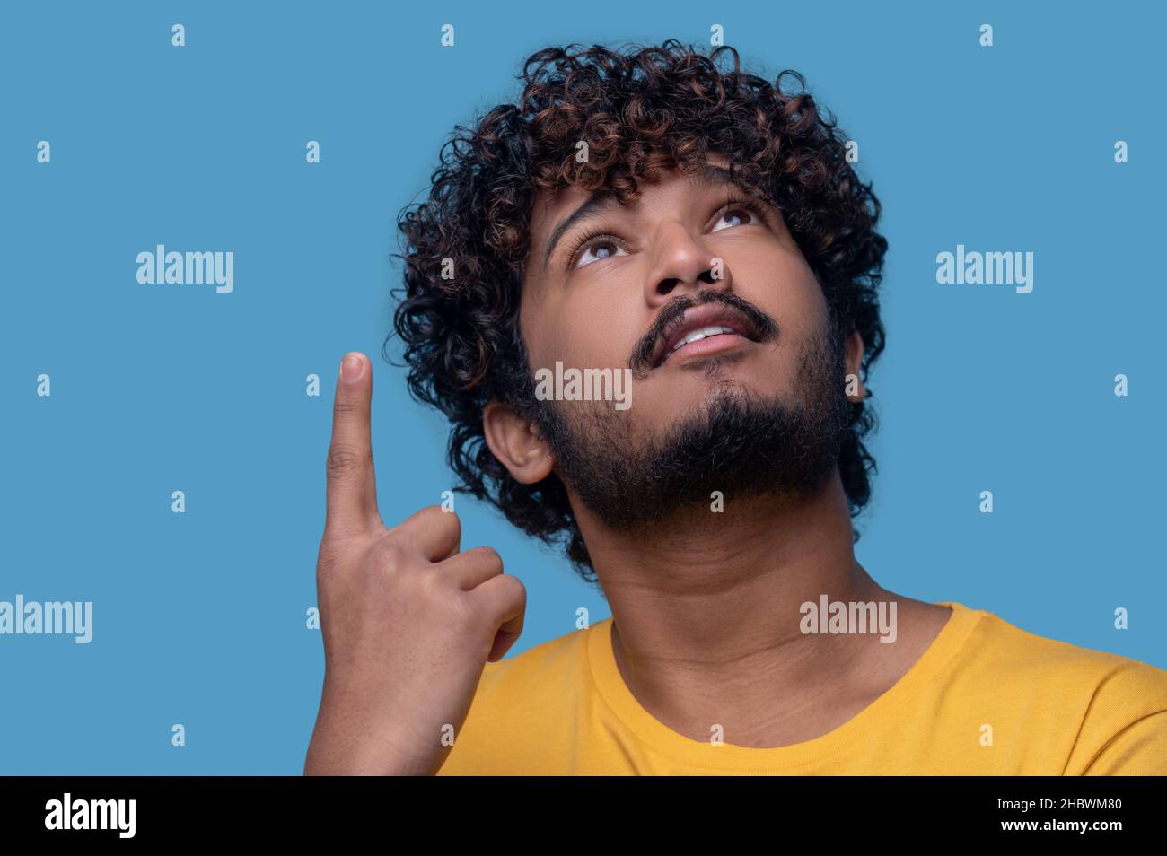 Concentrated man with the raised forefinger looking up at the ceiling ...