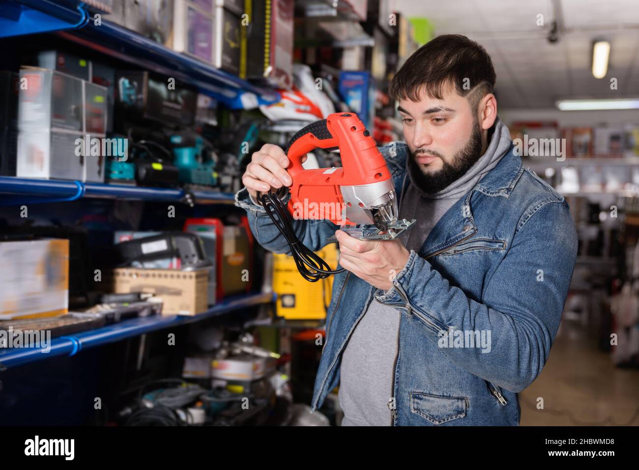 Confident buyer chooses an electric tool in hardware store Stock Photo ...