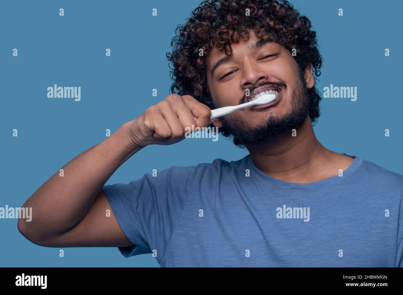 Pleased male using a toothbrush during the tooth-brushing procedure ...